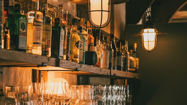 Uma área de bar com prateleiras de garrafas de bebidas e copos.
