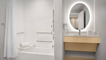 Uma casa de banho moderna com chuveiro, toucador com espelho e porta-toalhas.