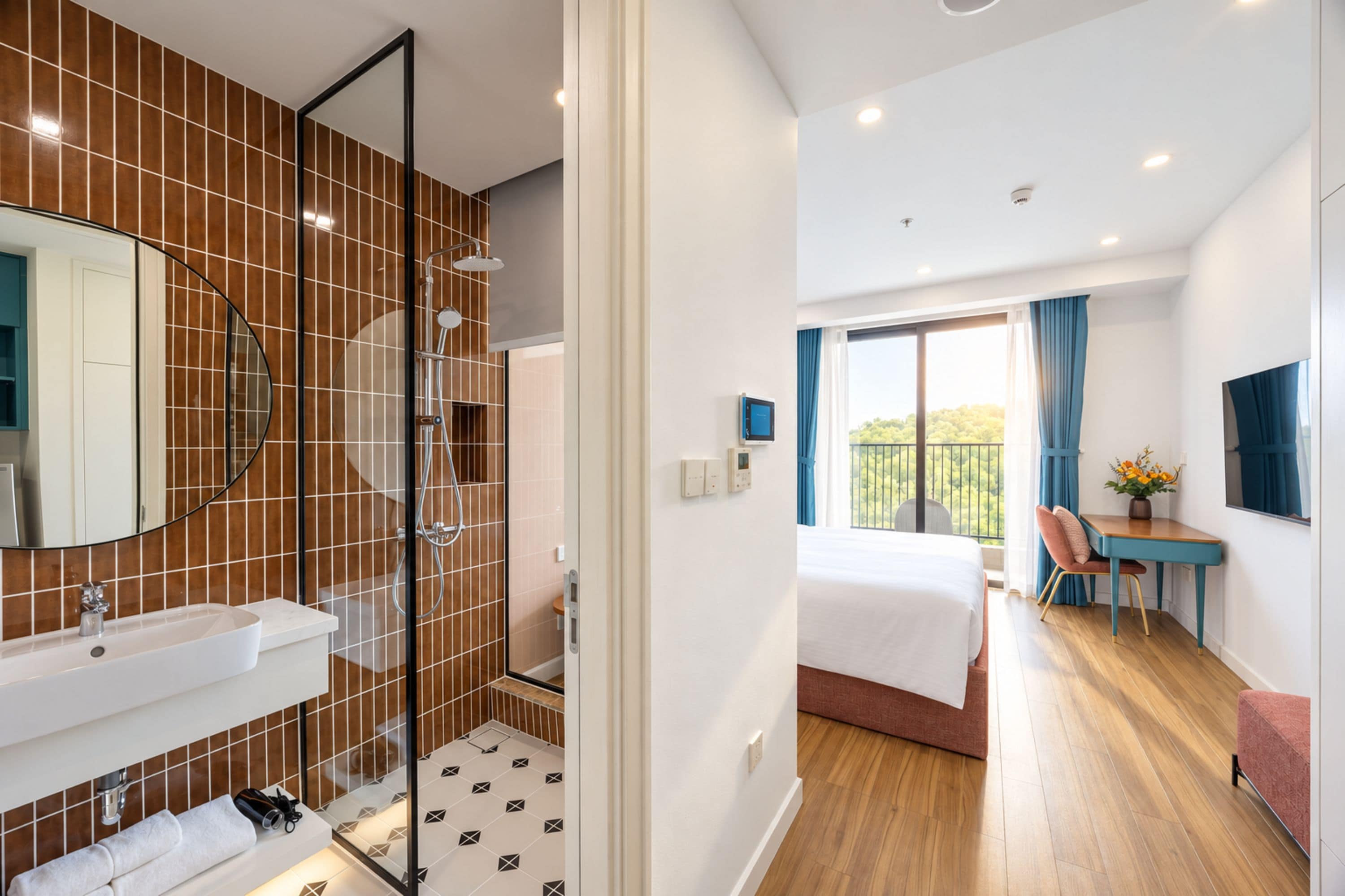 Quarto de hotel com banheiro, uma cama, escrivaninha e vista para o exterior.