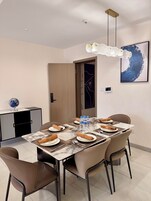 Uma área de refeições com mesa de mármore posta para quatro pessoas, com garrafas de água, pratos e talheres.