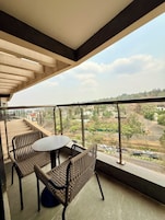 Varanda com mesa e cadeiras, vista para área residencial com árvores e edifícios.