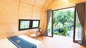 Um quarto aconchegante com uma cama, uma mesinha com uma planta e uma janela com vista para um jardim.
