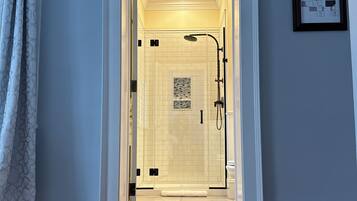 Um banheiro moderno com box de vidro, paredes revestidas de azulejos brancos e piso de madeira.