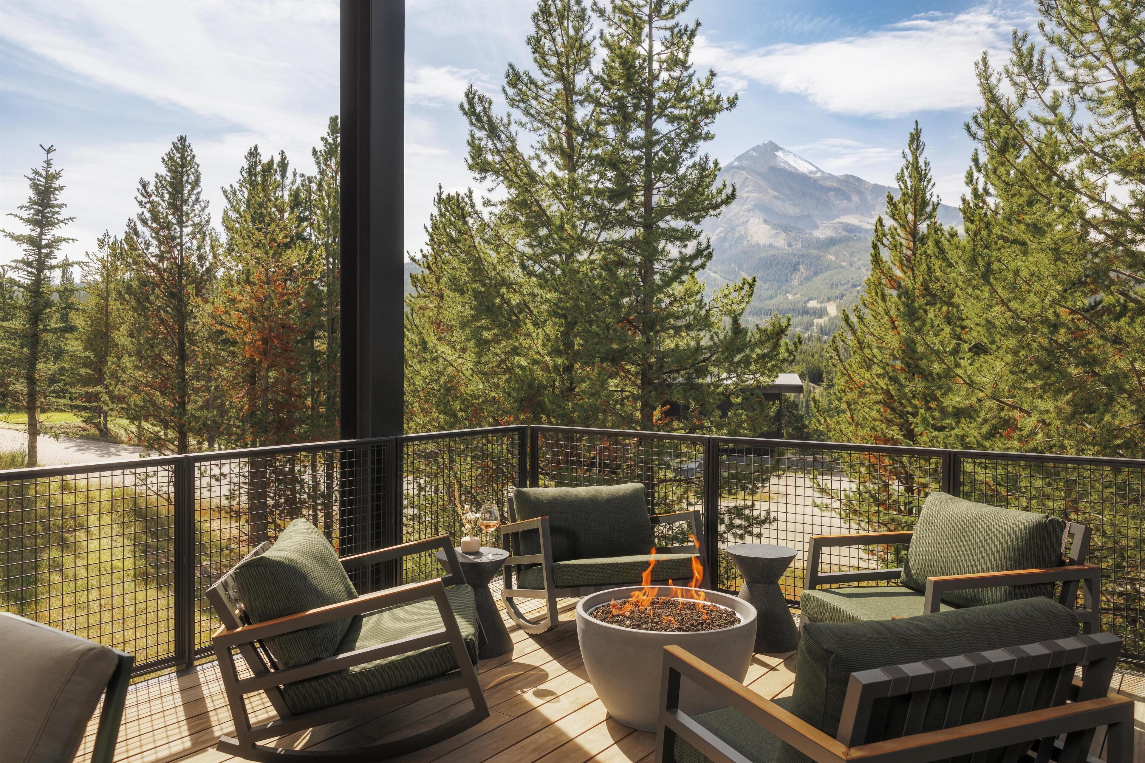 Um terraço com área de estar ao ar livre, lareira e vista para uma cordilheira.