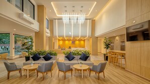 Um lobby espaçoso com balcão de recepção, área de estar e um lustre moderno.