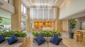 Um hall de hotel moderno com balcão de recepção, área de estar e uma grande planta.