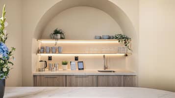 Uma cozinha moderna com bancada de mármore, pia embutida e máquina de café.