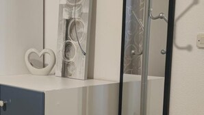 Casa de banho com toucador branco, objeto decorativo em forma de coração e espelho com moldura preta.