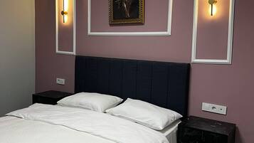 Quarto com cama, duas mesas de cabeceira e luminárias fixadas na parede.