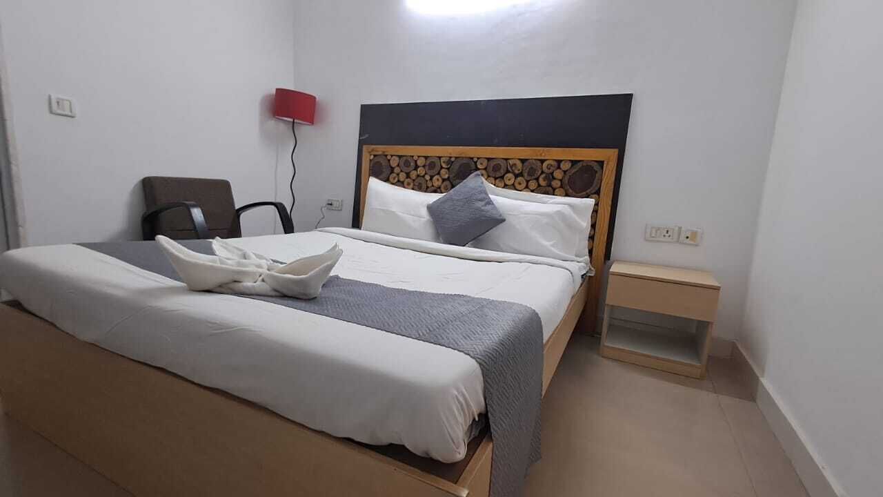 Uma cama bem arrumada com cabeceira de madeira, mesa de cabeceira e uma cadeira.