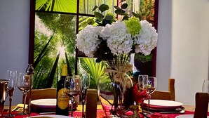 Uma mesa de jantar posta com flores brancas, copos de vinho e uma garrafa de vinho.