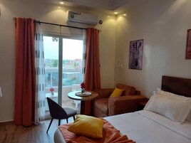Quarto de hotel com uma cama, uma cadeira, uma mesa pequena e vista para o exterior.