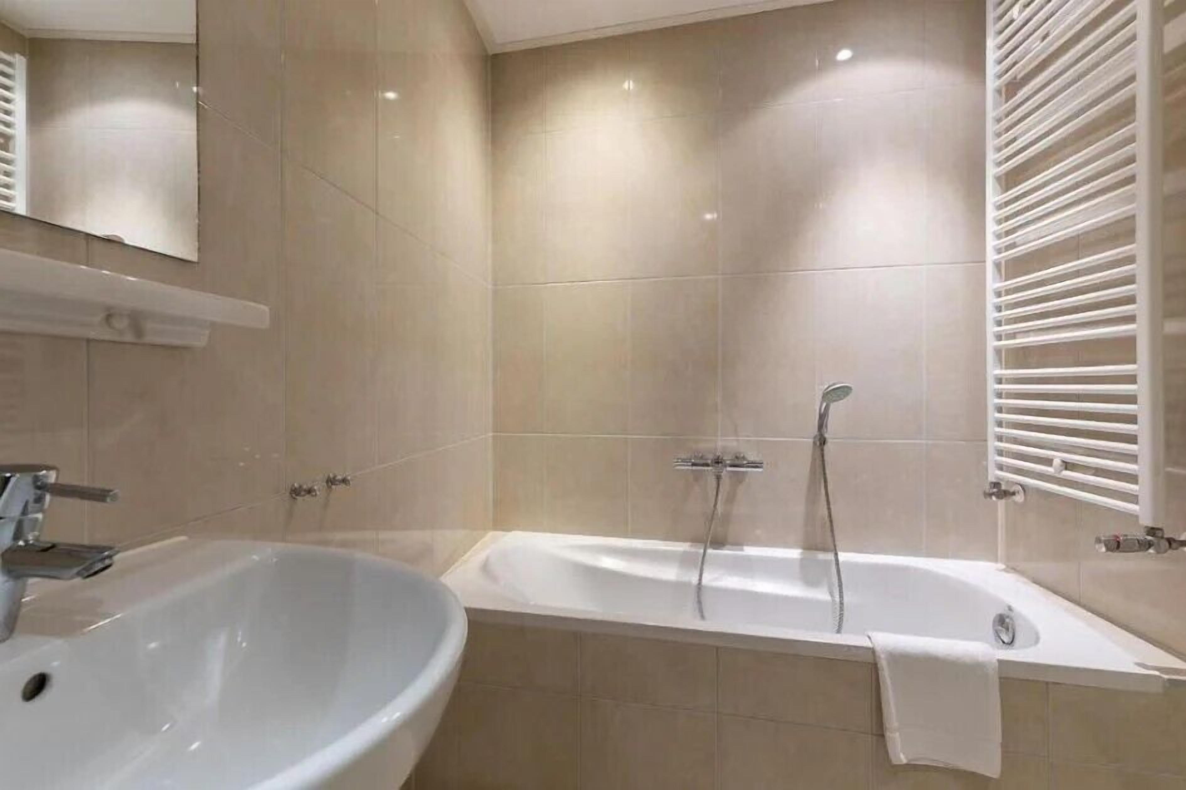 Uma casa de banho moderna com uma banheira branca grande, uma pia e um espelho.
