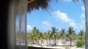 Vista de uma praia com palmeiras e céu claro.