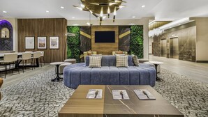 Um lobby moderno com área de estar central, espaço para refeições e balcão de recepção.