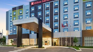 Um hotel Hilton Garden Inn com fachada moderna, grandes janelas e entrada destacada.