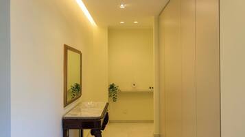 Um corredor com uma mesa de mármore, um espelho e uma planta.