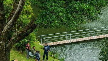 Um grupo de pessoas perto de um lago com um píer e um barco pequeno.