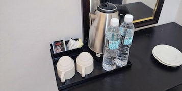 Estação de café com um coador, duas xícaras, duas garrafas de água e uma bandeja com uma xícara de café e alguns papéis.