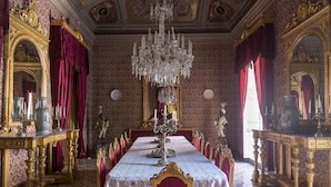 Uma sala de jantar imponente com uma mesa comprida, lustres elaborados e decoração de parede requintada.