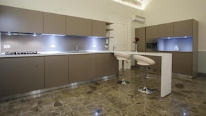 Cozinha moderna com ilha central, banquetas de bar e eletrodomésticos embutidos.