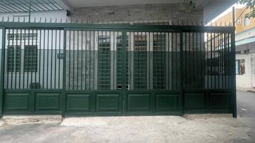 Uma entrada com portão, cerca de metal e muro de tijolos.