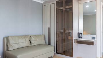 Quarto moderno com sofá bege, closet espaçoso e pequena toucador com espelho.