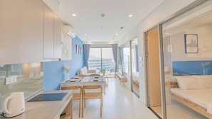 Quarto de hotel moderno com área de refeições, cama e vista da cidade.