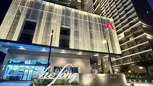 Um hotel moderno com fachada marcante, caracterizada por linhas verticais e uma bandeira vermelha proeminente.