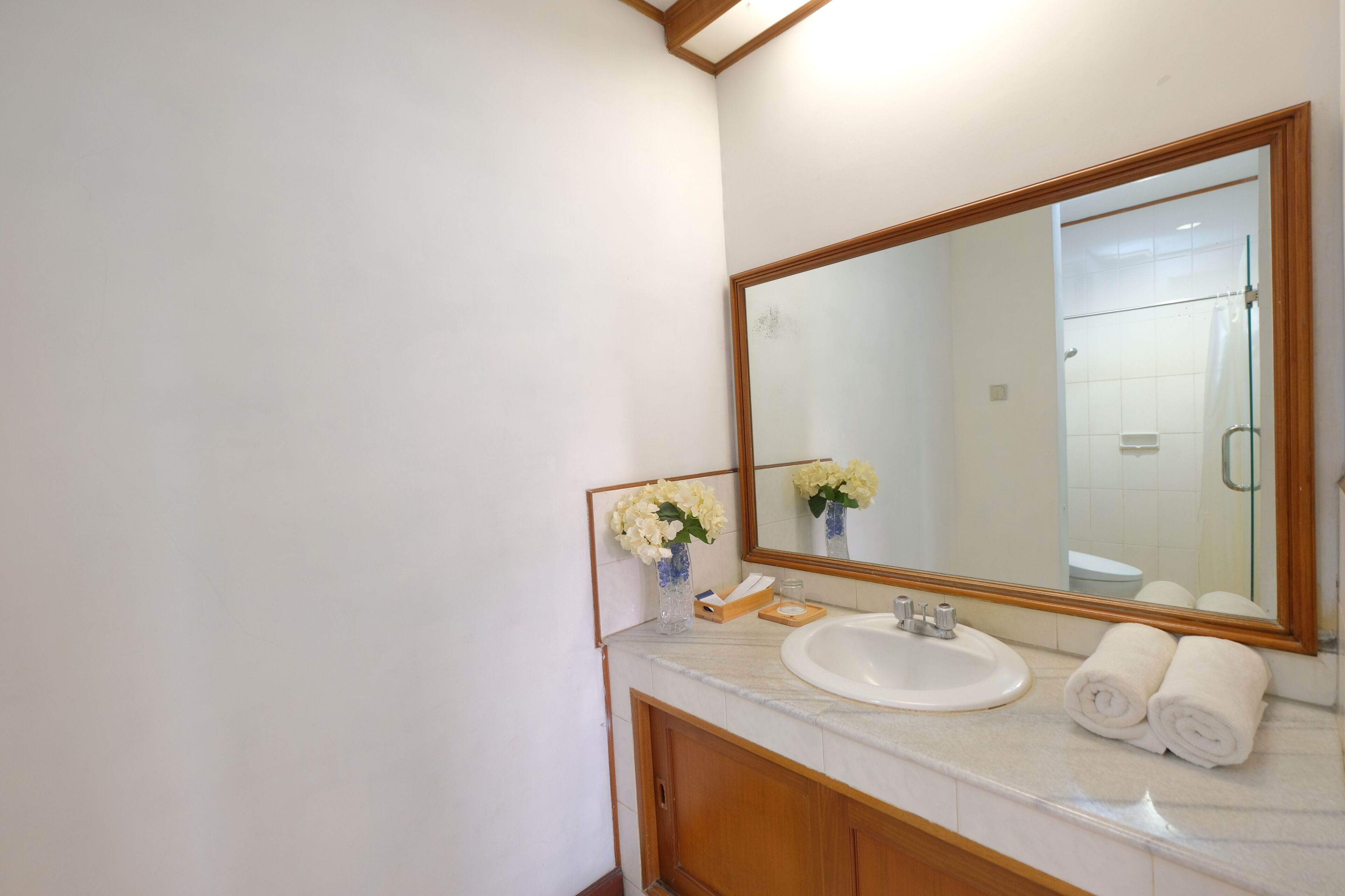 Uma casa de banho com uma pia branca, um espelho e um armário de madeira.