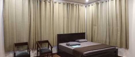 Quarto com cama, duas cadeiras e um ventilador de teto.