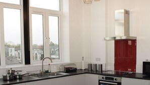 Cozinha moderna com uma janela grande, eletrodomésticos de aço inoxidável e uma parede de destaque vermelha.