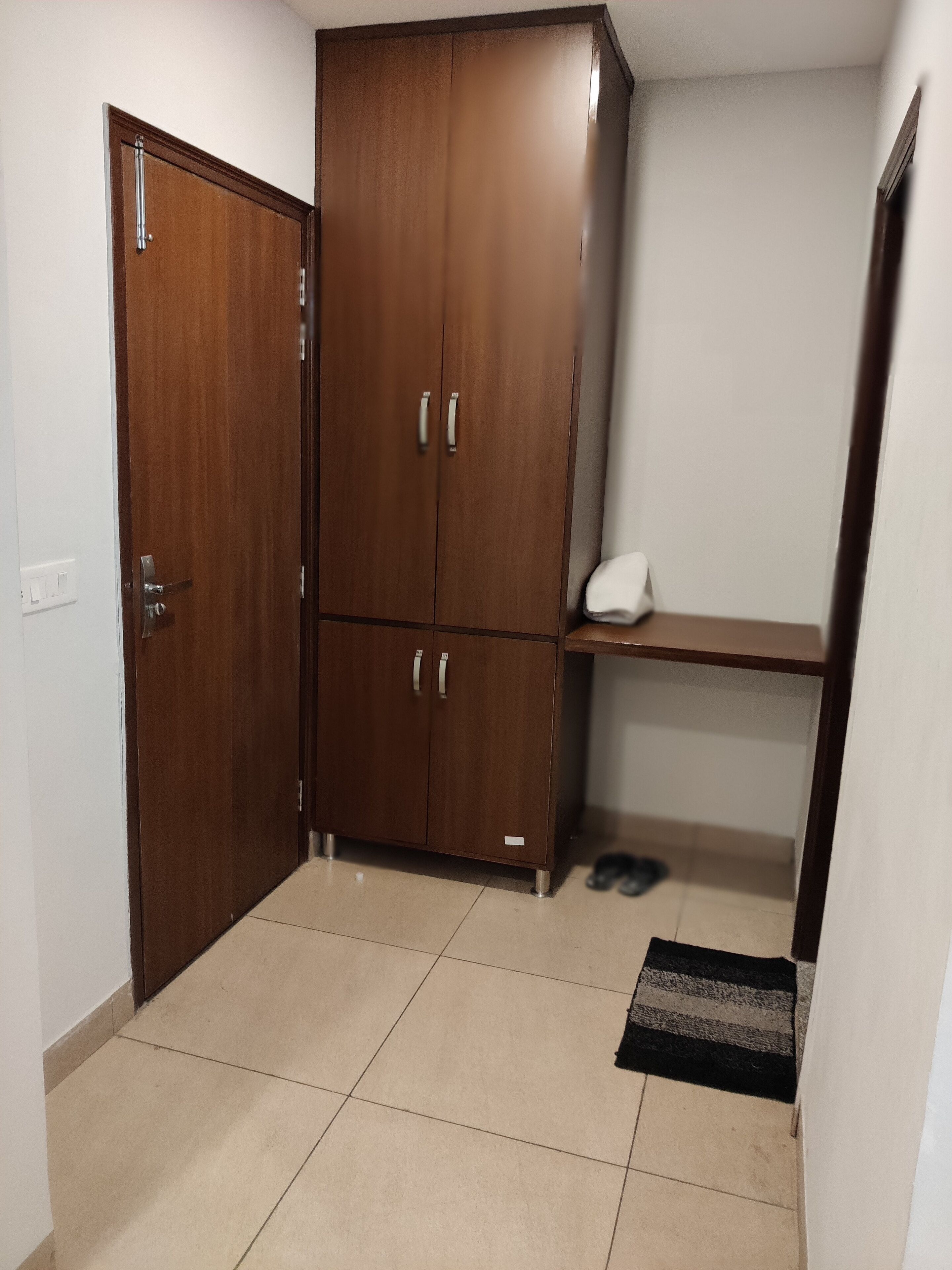 Quarto com guarda-roupa de madeira, mesa de cabeceira branca e tapete riscado em preto e branco.