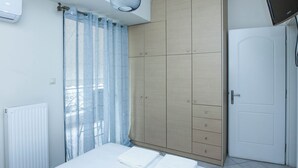 Quarto com cama, guarda-roupa, porta e luminária pendente.