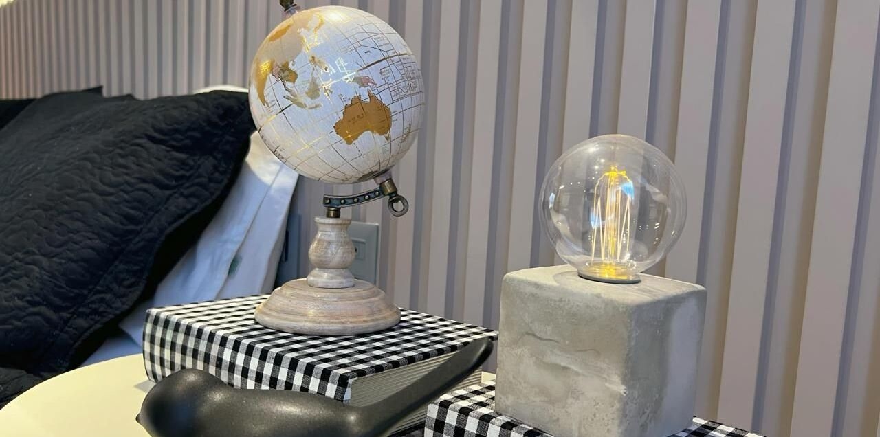 Um globo em um suporte, uma esfera de vidro transparente e um objeto preto sobre uma toalha xadrez.