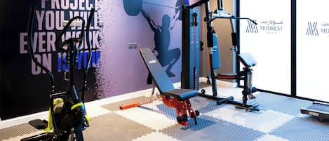 Uma academia com equipamentos de ginástica, um painel de motivação e um balcão de recepção.