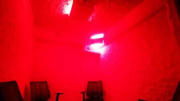 Um quarto com iluminação vermelha, com três cadeiras dispostas em fila.