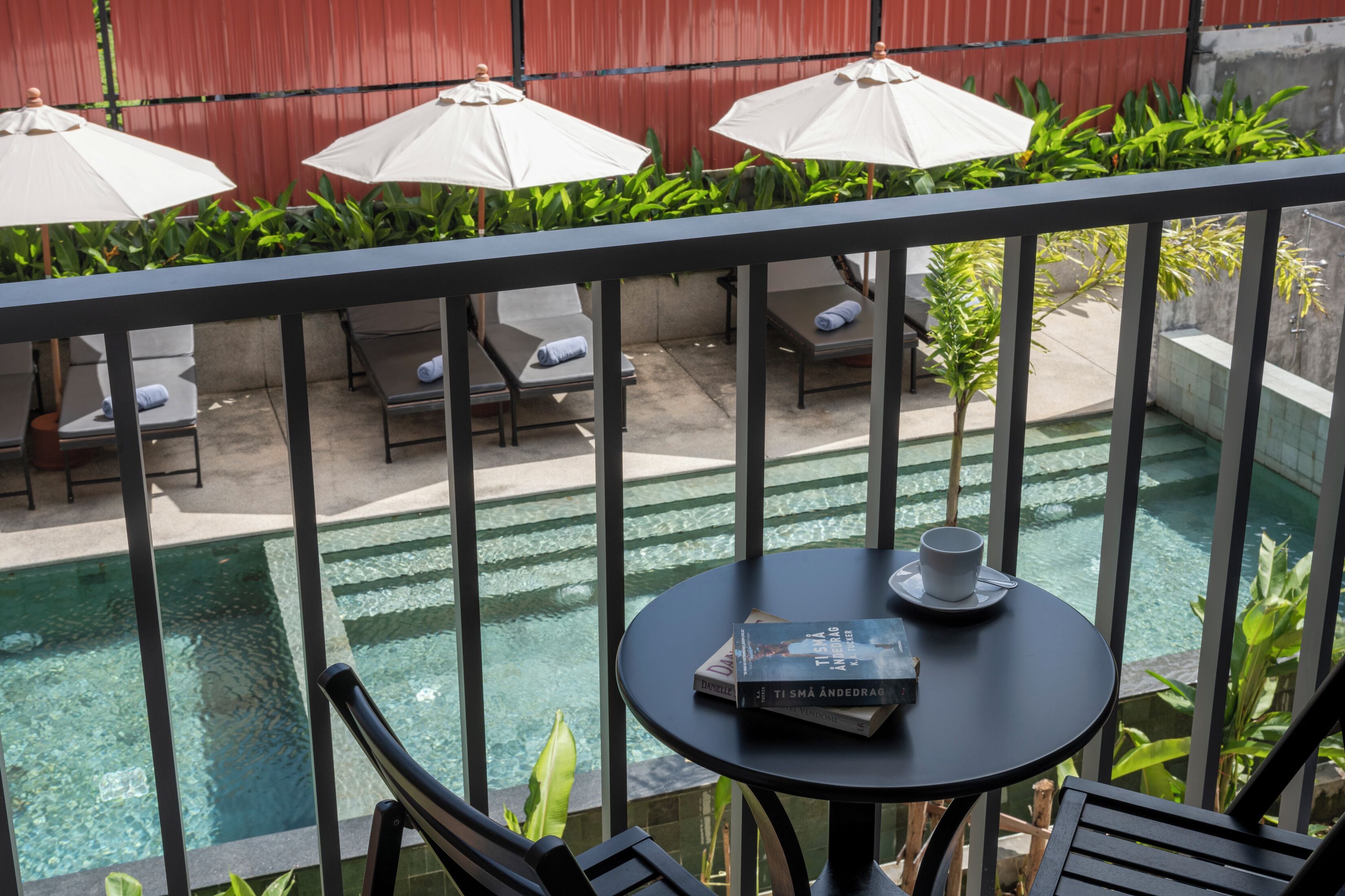 Varanda com piscina, espreguiçadeiras e guarda-sóis.