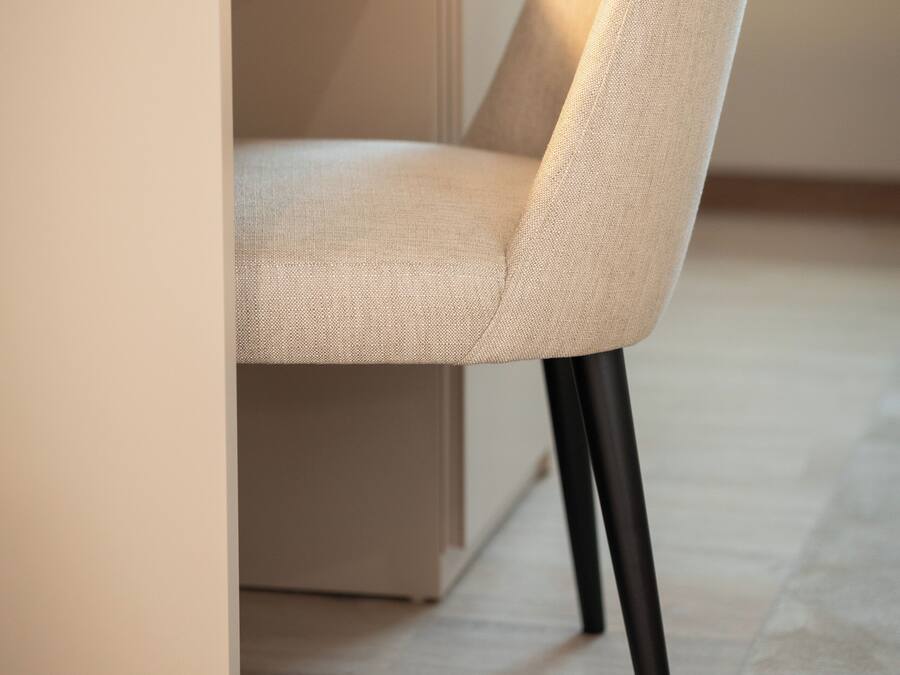 Uma área de refeições moderna com uma mesa de cor clara e uma cadeira com pernas pretas.