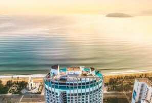 Hotel moderno com piscina no terraço e vista para a praia.