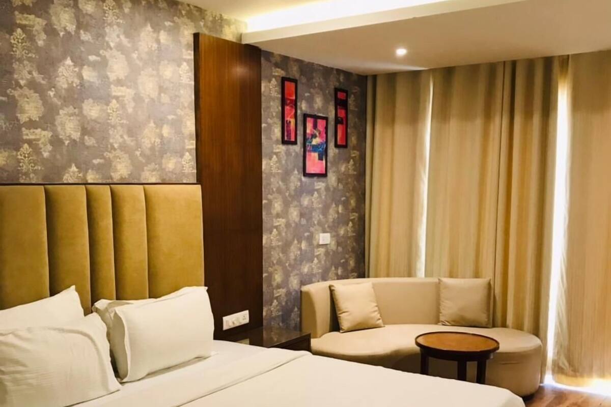 Quarto de hotel com uma cama grande, um sofá, uma mesinha redonda e um ventilador de teto.