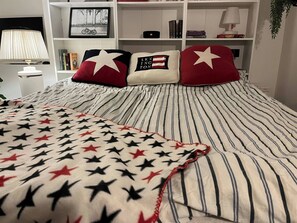 Uma cama bem arrumada com colcha listrada e travesseiros com estrelas e listras.