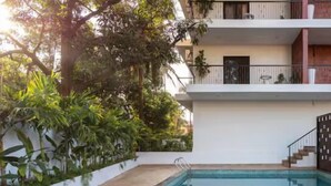 Um edifício moderno de vários andares com piscina, varandas e vegetação exuberante.