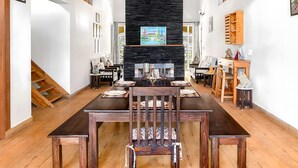 Uma sala de jantar com uma mesa de madeira comprida, cadeiras e uma lareira de pedra preta.