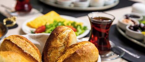 Uma mesa com pão, uma salada e um copo de chá.