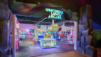 Um salão de jogos indoor com várias máquinas de jogos e uma placa com a inscrição 'Northern Lights Arcade'.