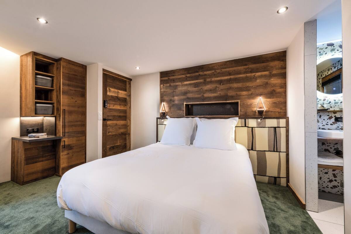 Quarto moderno com cabeceira de madeira, uma cama grande e armários embutidos.