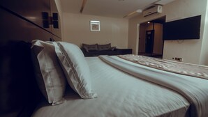 Quarto de hotel moderno com uma cama grande, televisão de tela plana fixada na parede e ar condicionado integrado.