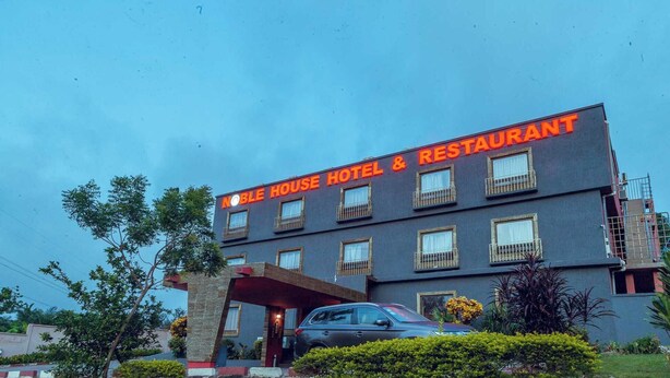 Um edifício de vários andares com uma placa que diz 'Noble House Hotel & Restaurant'.