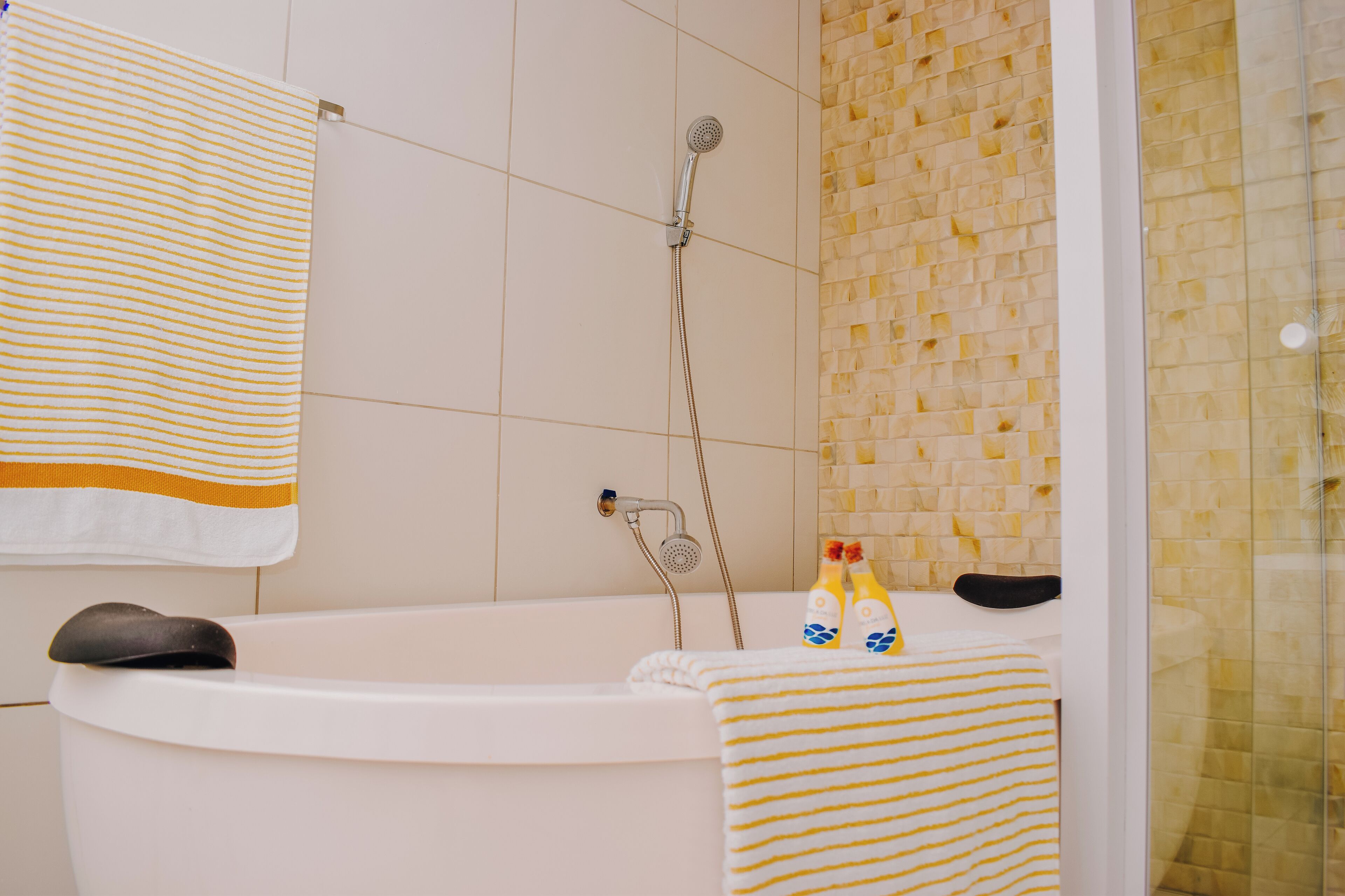 Um banheiro com banheira, chuveiro e parede revestida de azulejos.